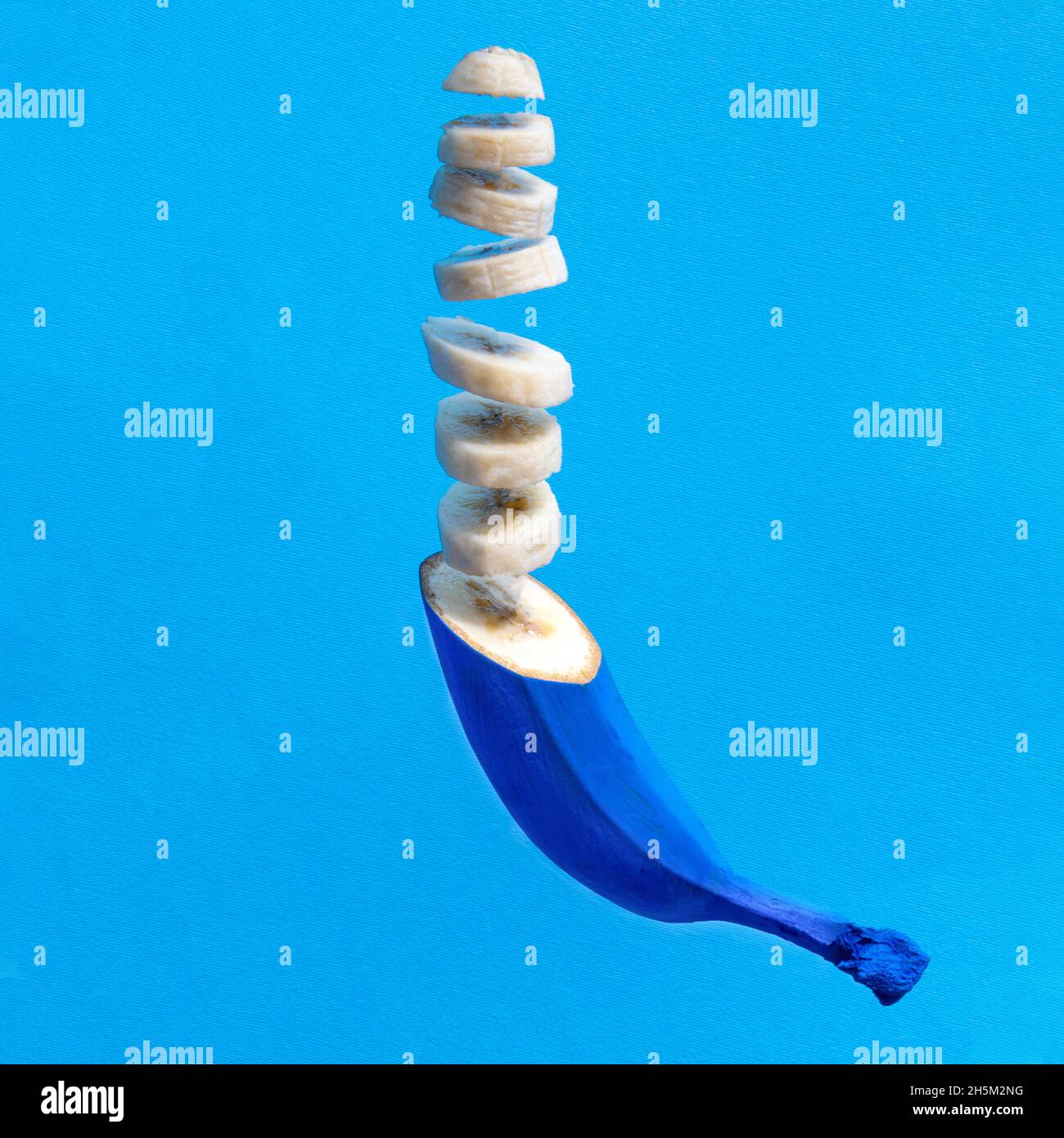 Banana with floating slices on a blue background Stock Photo - Alamy