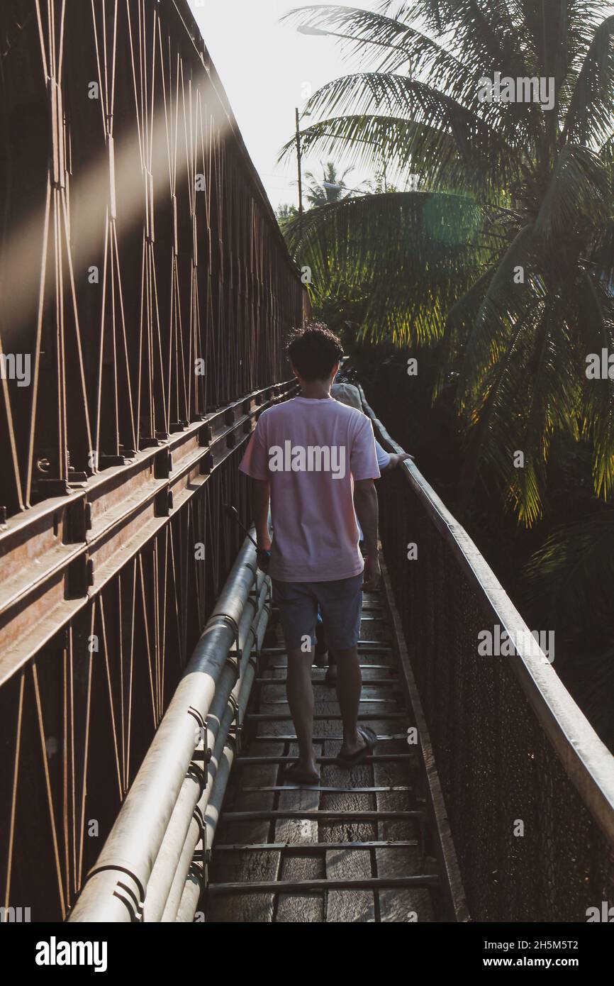 Vertical shot of a man walking on a pedestrian walkway of a truss ...