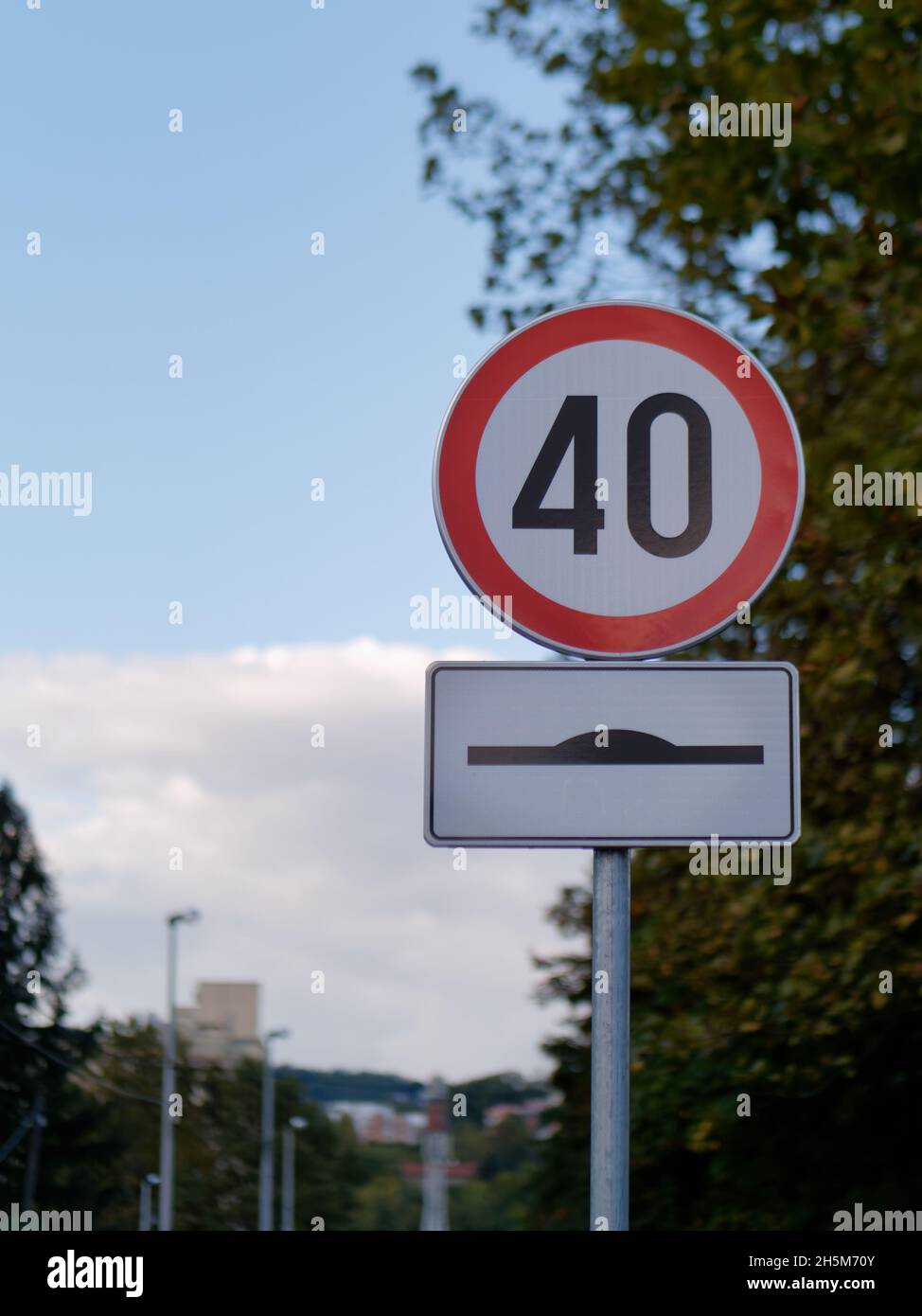 Vertical shot of a round speed limit 40 sign and a hump sign attached ...