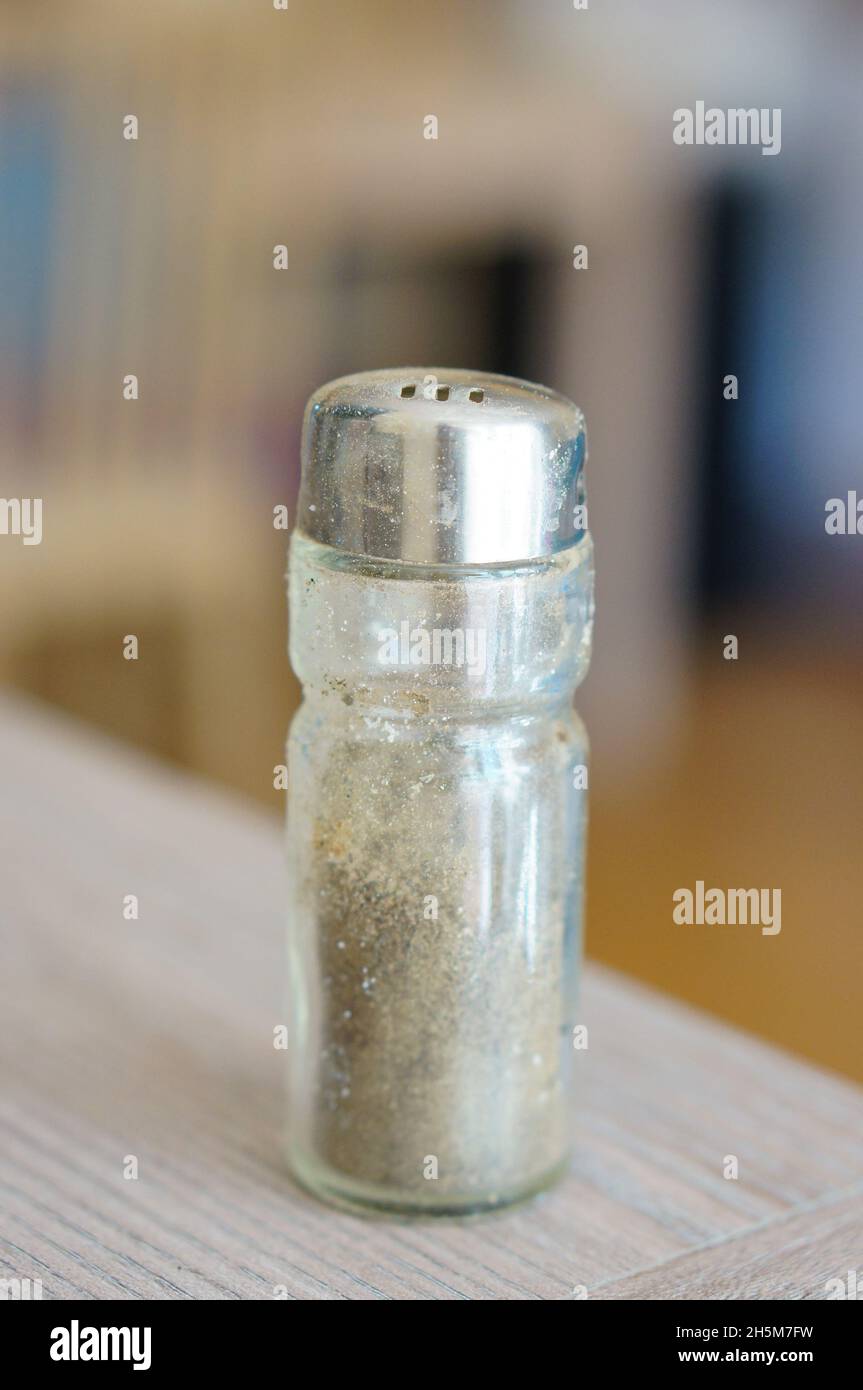 Black pepper shaker on the table in the blurred background Stock Photo ...