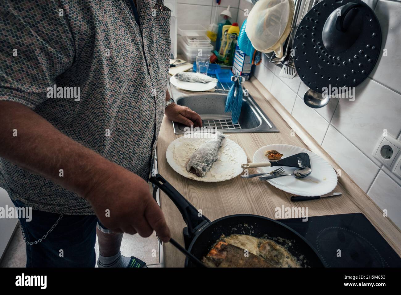 Man cooking fish in the kitchen Stock Photo - Alamy