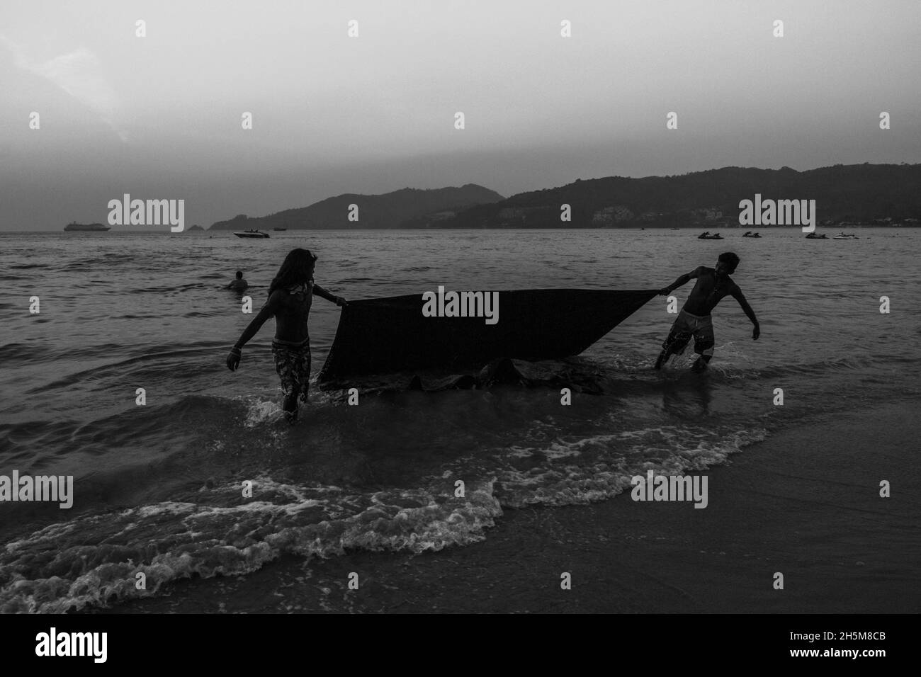 Grayscale shot of people pulling out from the sea on a beach Stock ...