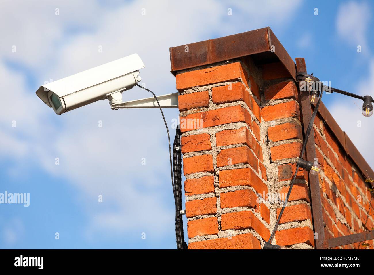 White CCTV camera is on high point of a red brick wall Stock Photo - Alamy