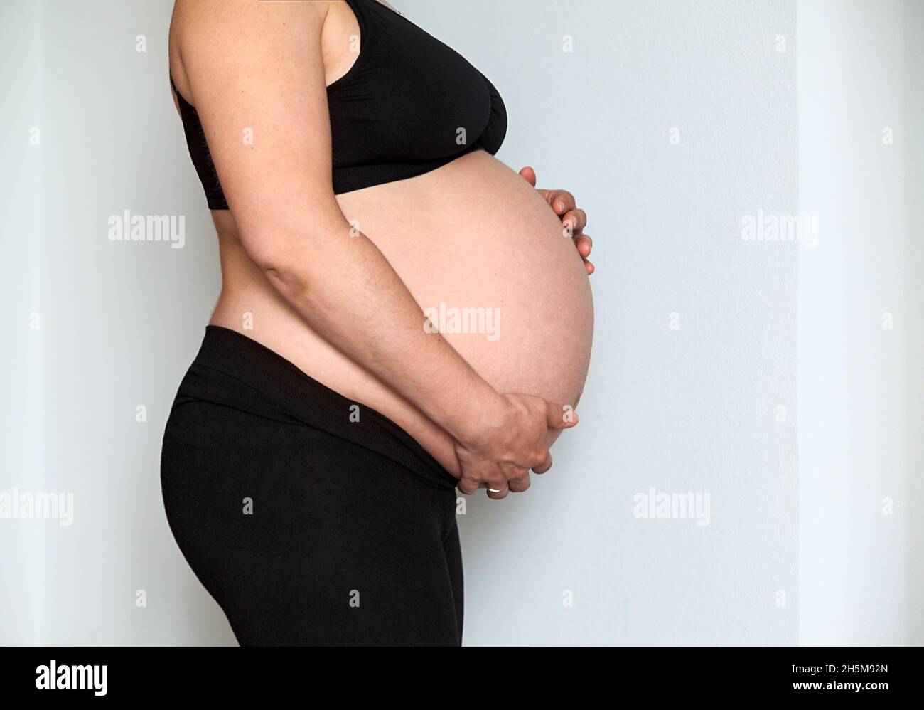 Side View At Pregnant Caucasian Woman With Big Belly Female Holding Hands Her Abdomen Stock