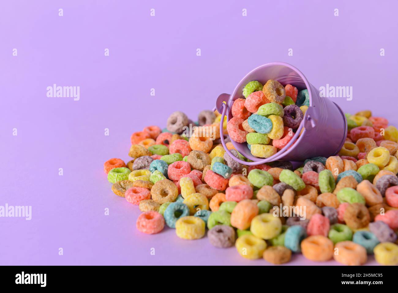 Small bucket with crunchy corn flakes rings on color background Stock ...