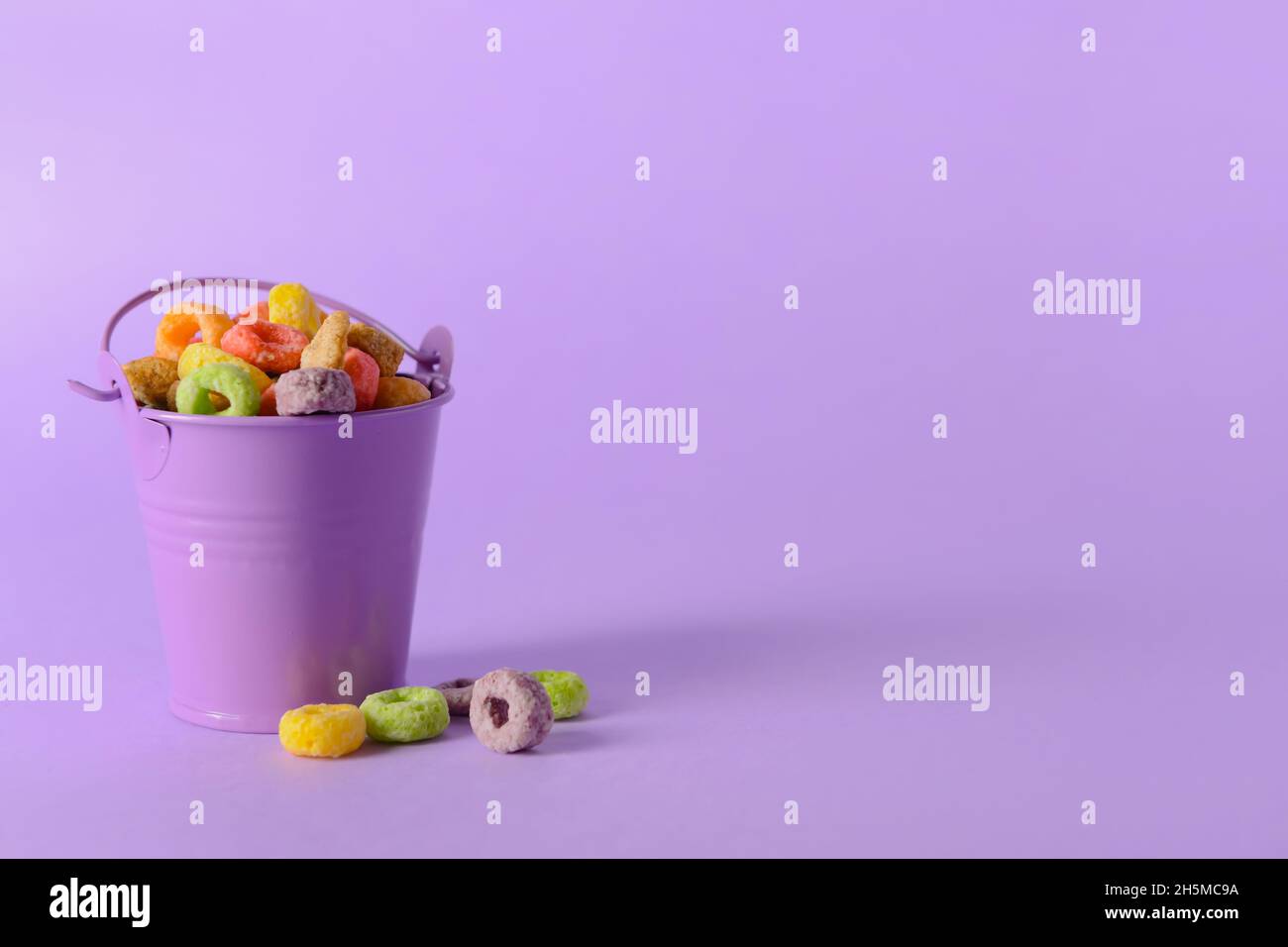 Small bucket with crunchy corn flakes rings on color background Stock ...