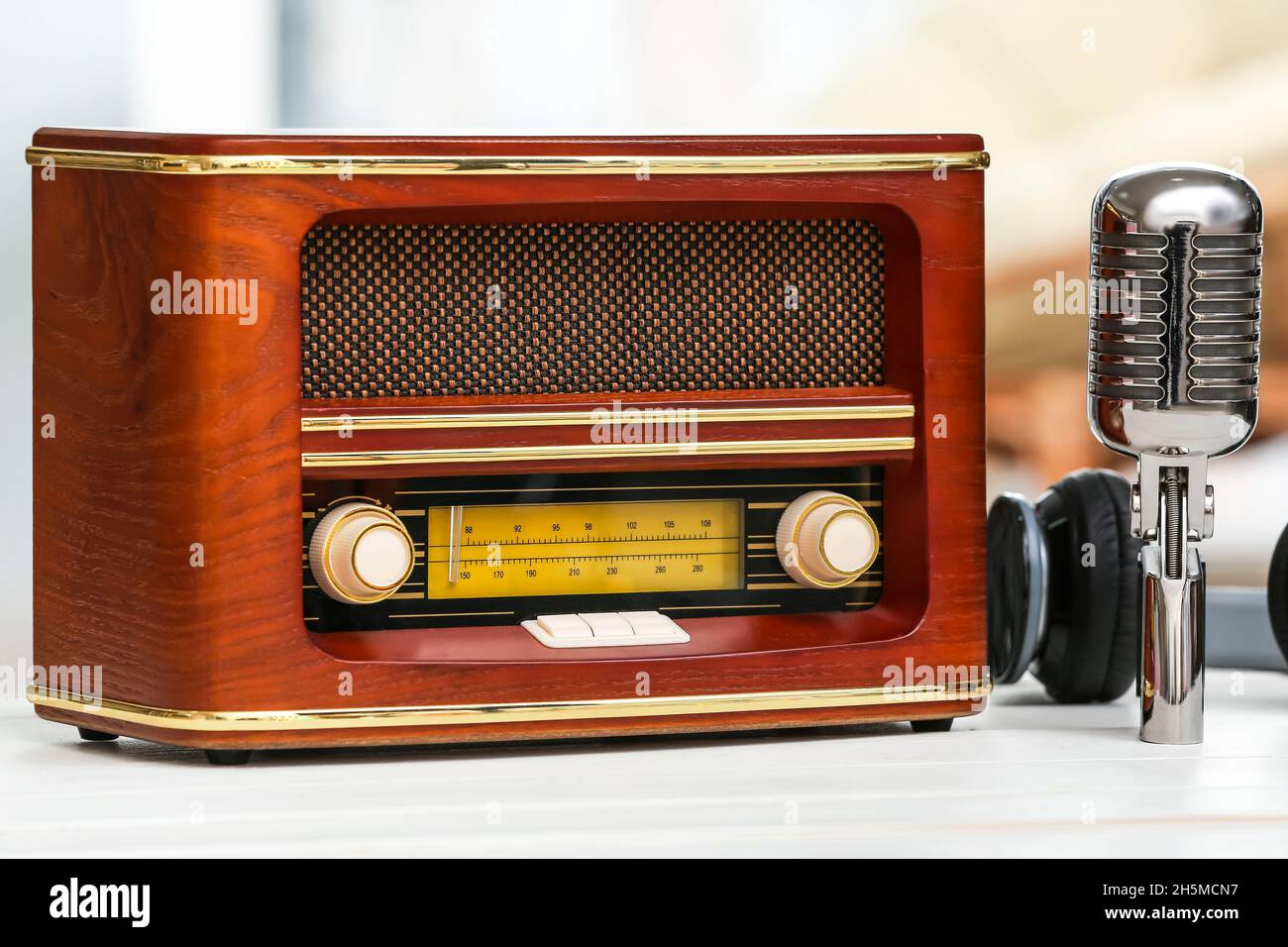 Retro radio receiver with microphone and headphones on table in room ...
