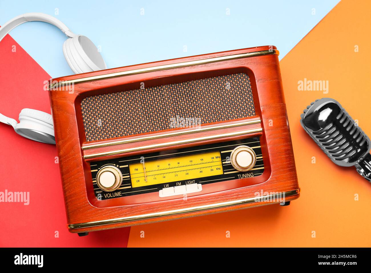 Retro radio receiver with microphone and headphones on color background ...