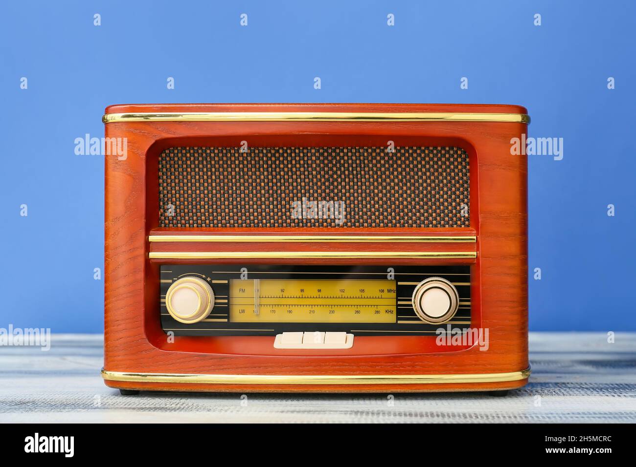Retro radio receiver on table against color background Stock Photo - Alamy