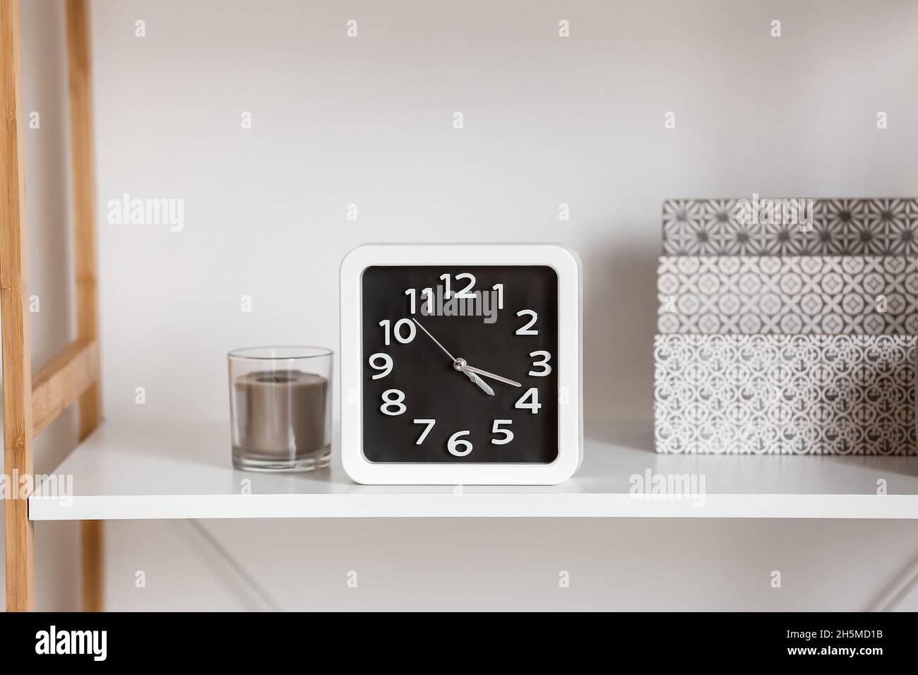 Clock with decor on shelf in room Stock Photo - Alamy