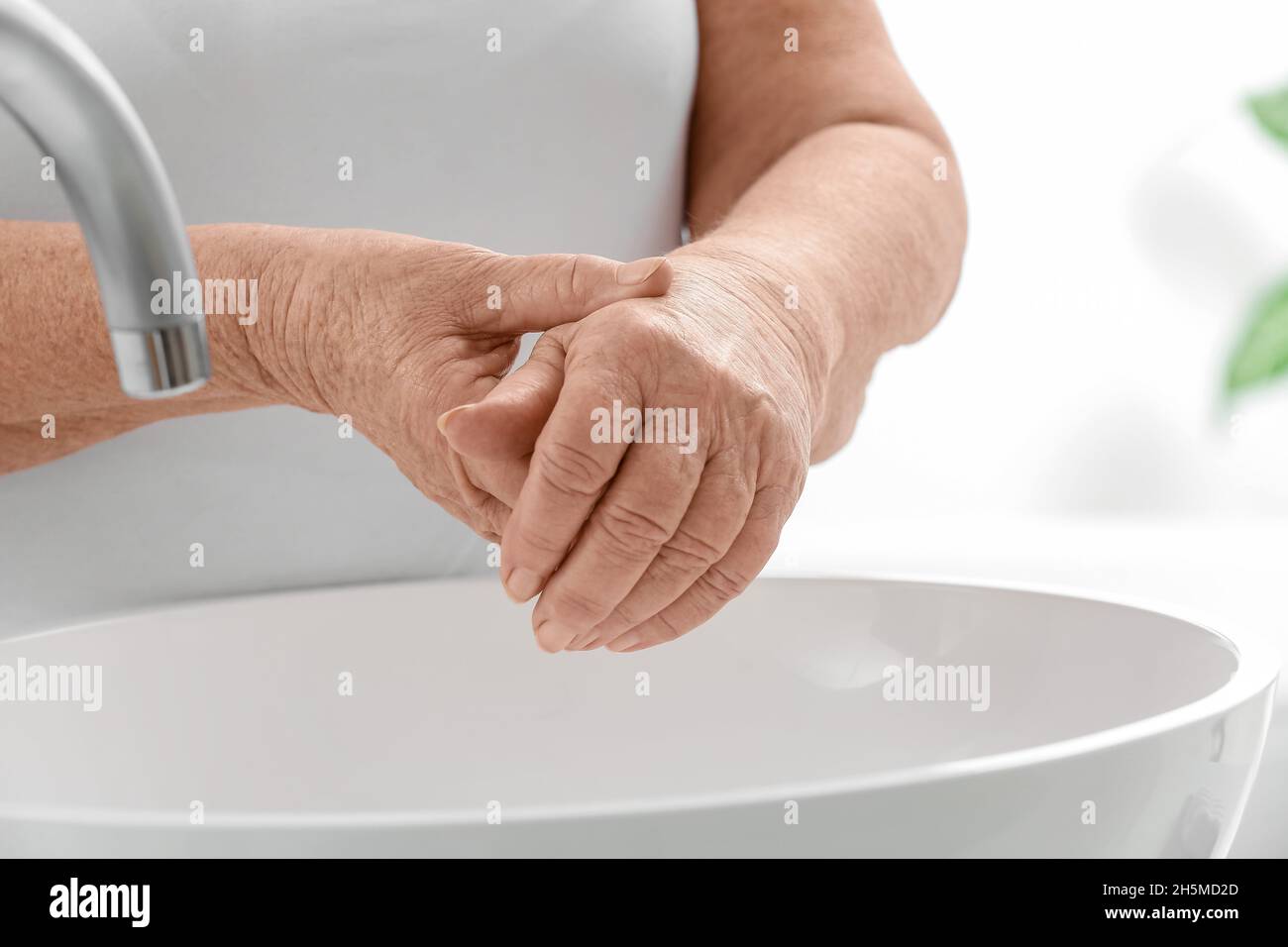 Elderly woman washing hands in bathroom Stock Photo - Alamy