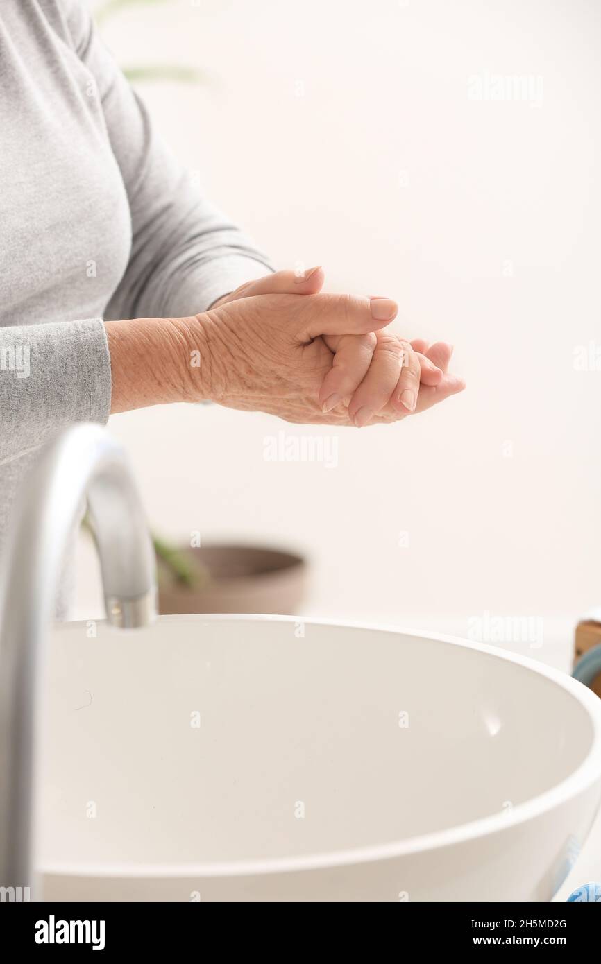 Elderly woman washing hands in bathroom Stock Photo - Alamy
