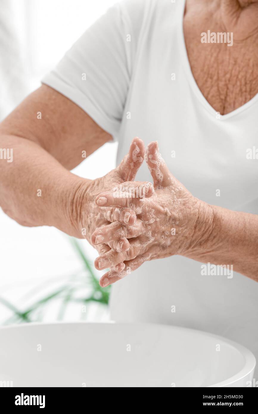 Elderly woman washing hands in bathroom Stock Photo - Alamy
