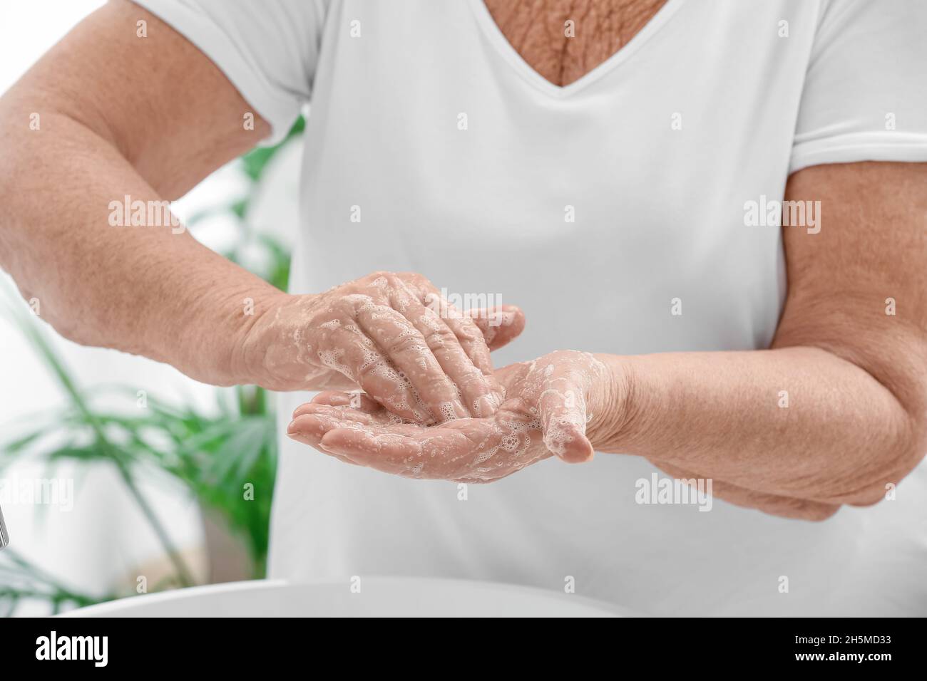 Elderly woman washing hands in bathroom Stock Photo - Alamy