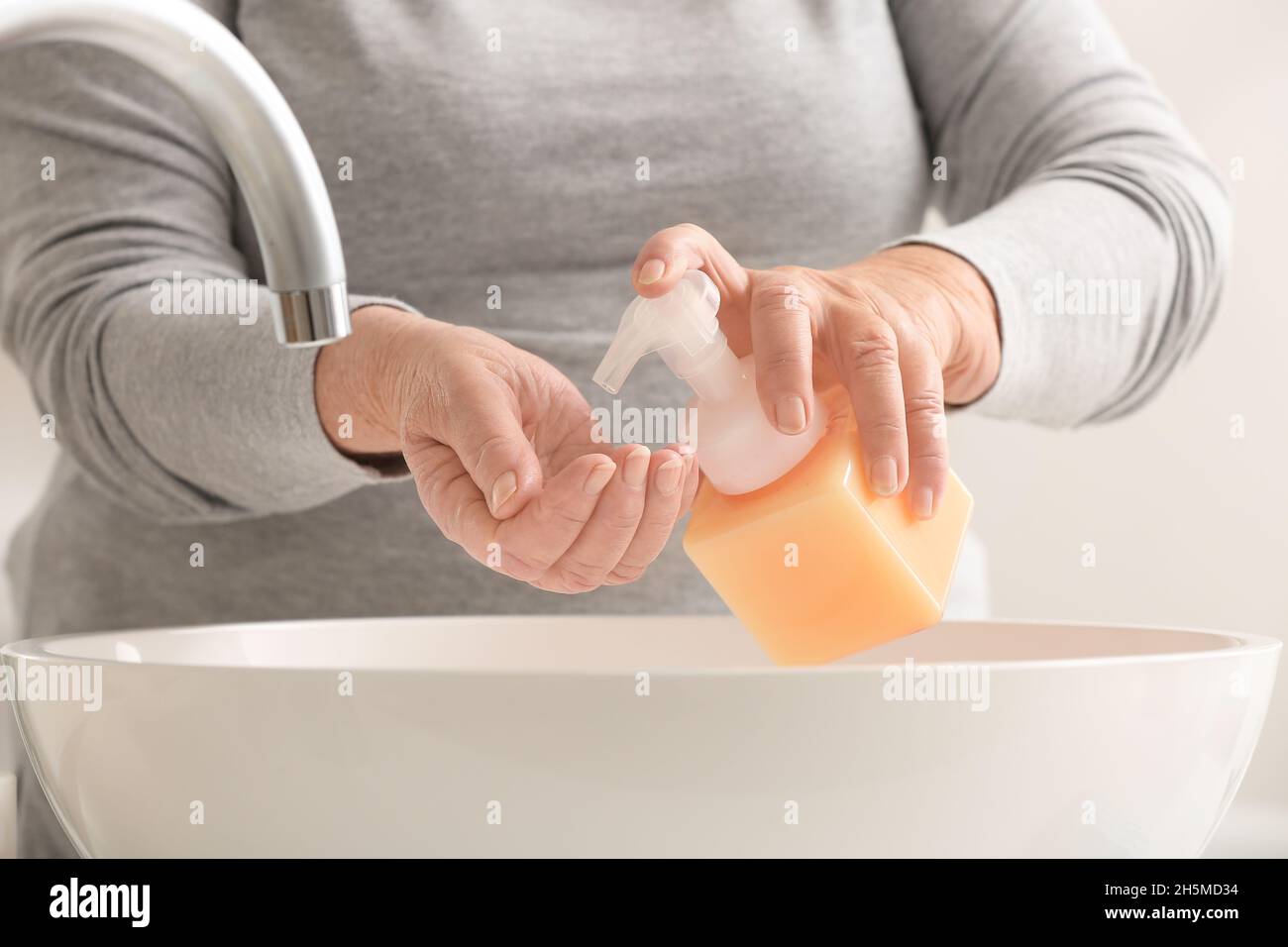 Elderly woman washing hands in bathroom Stock Photo - Alamy