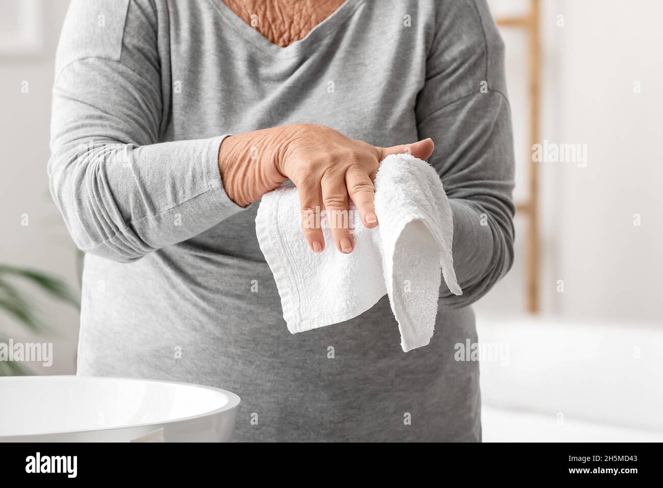 Elderly woman washing hands in bathroom Stock Photo - Alamy