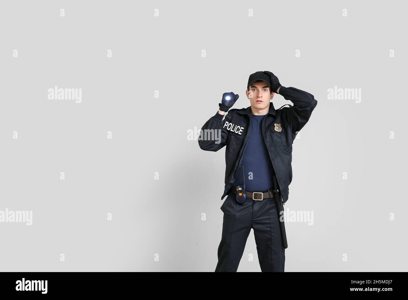 Shocked young policeman with flashlight on light background Stock Photo ...