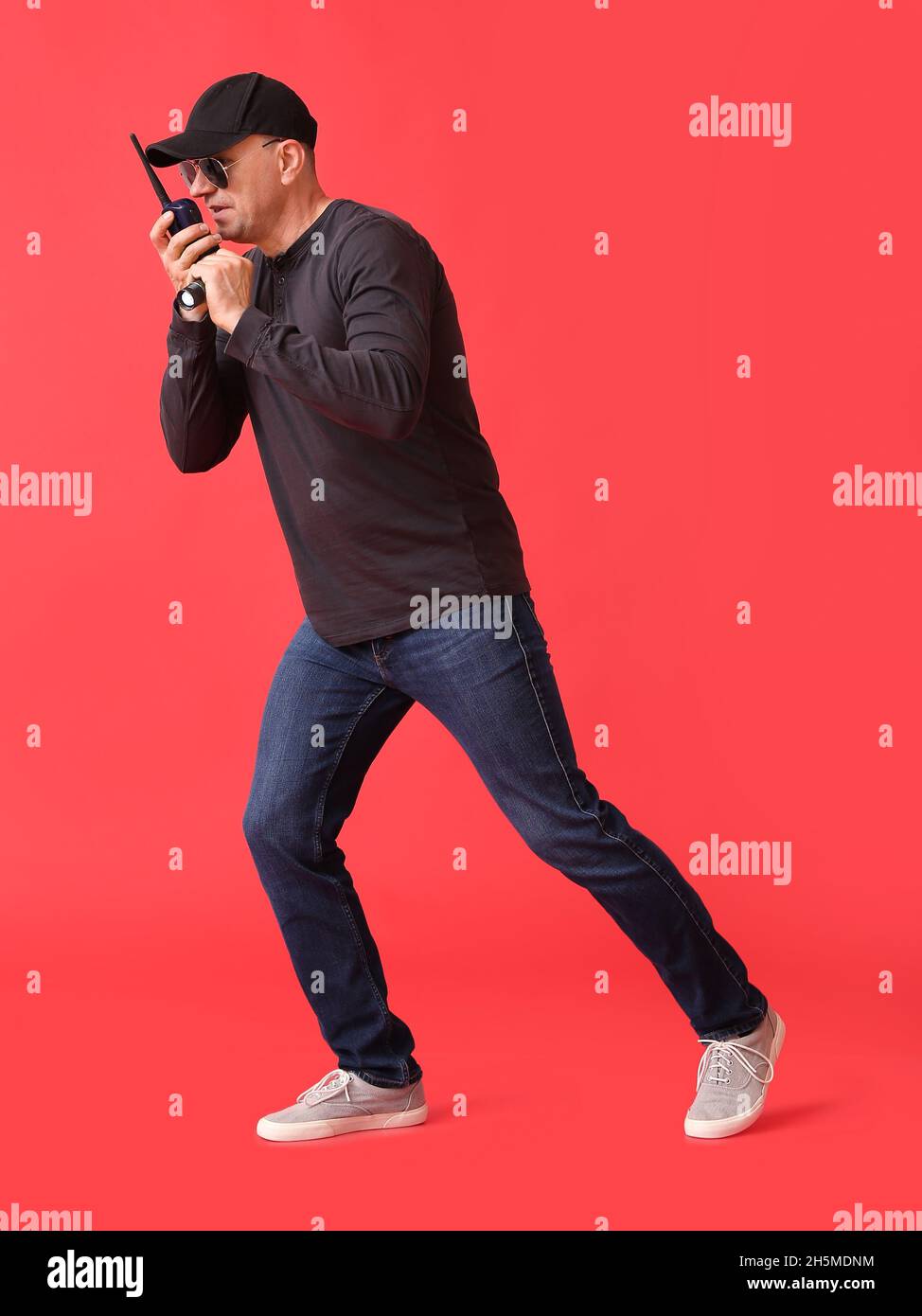 Mature man with two-way radio and flashlight on red background Stock ...