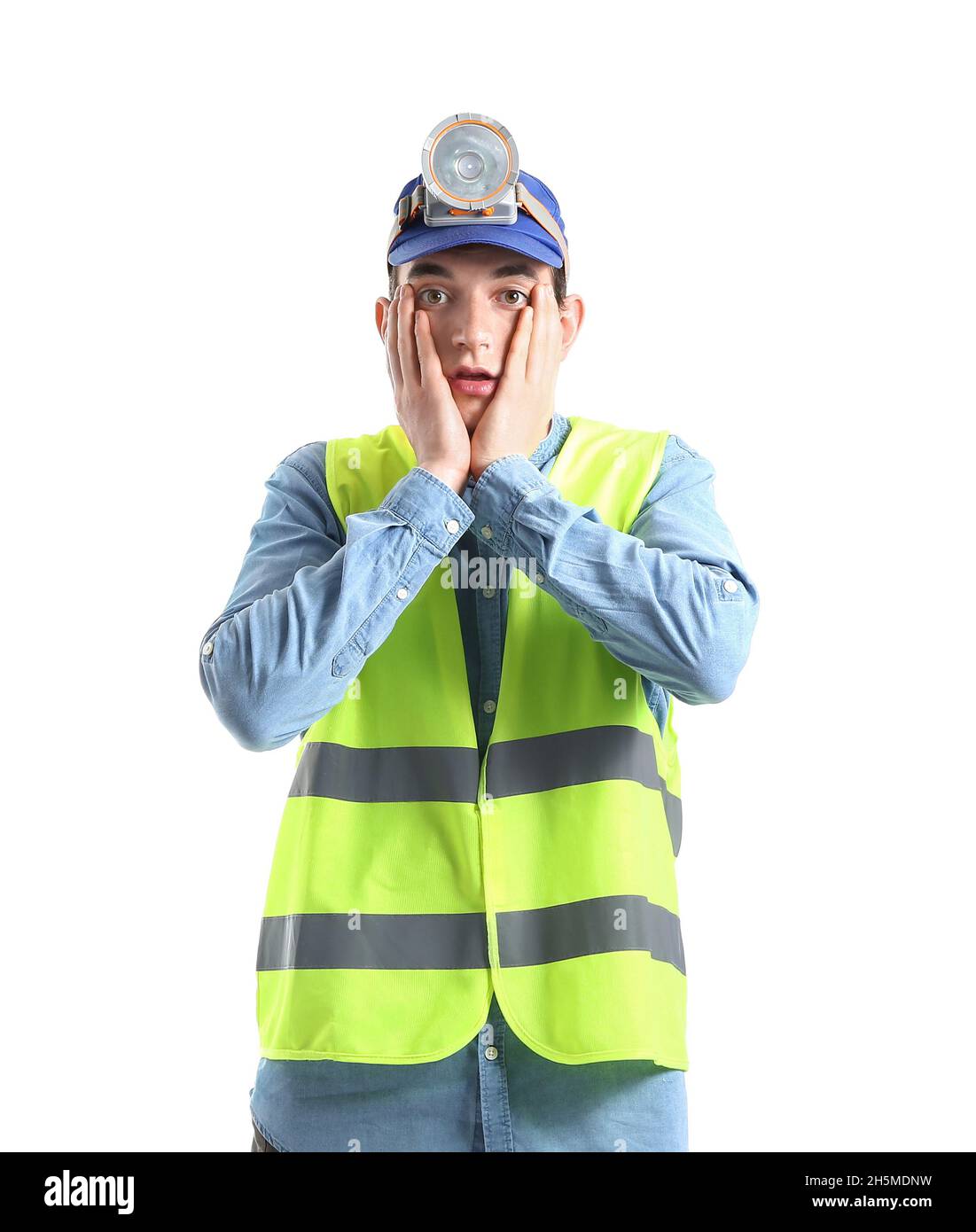 Shocked young male worker with headlamp flashlight on white background ...