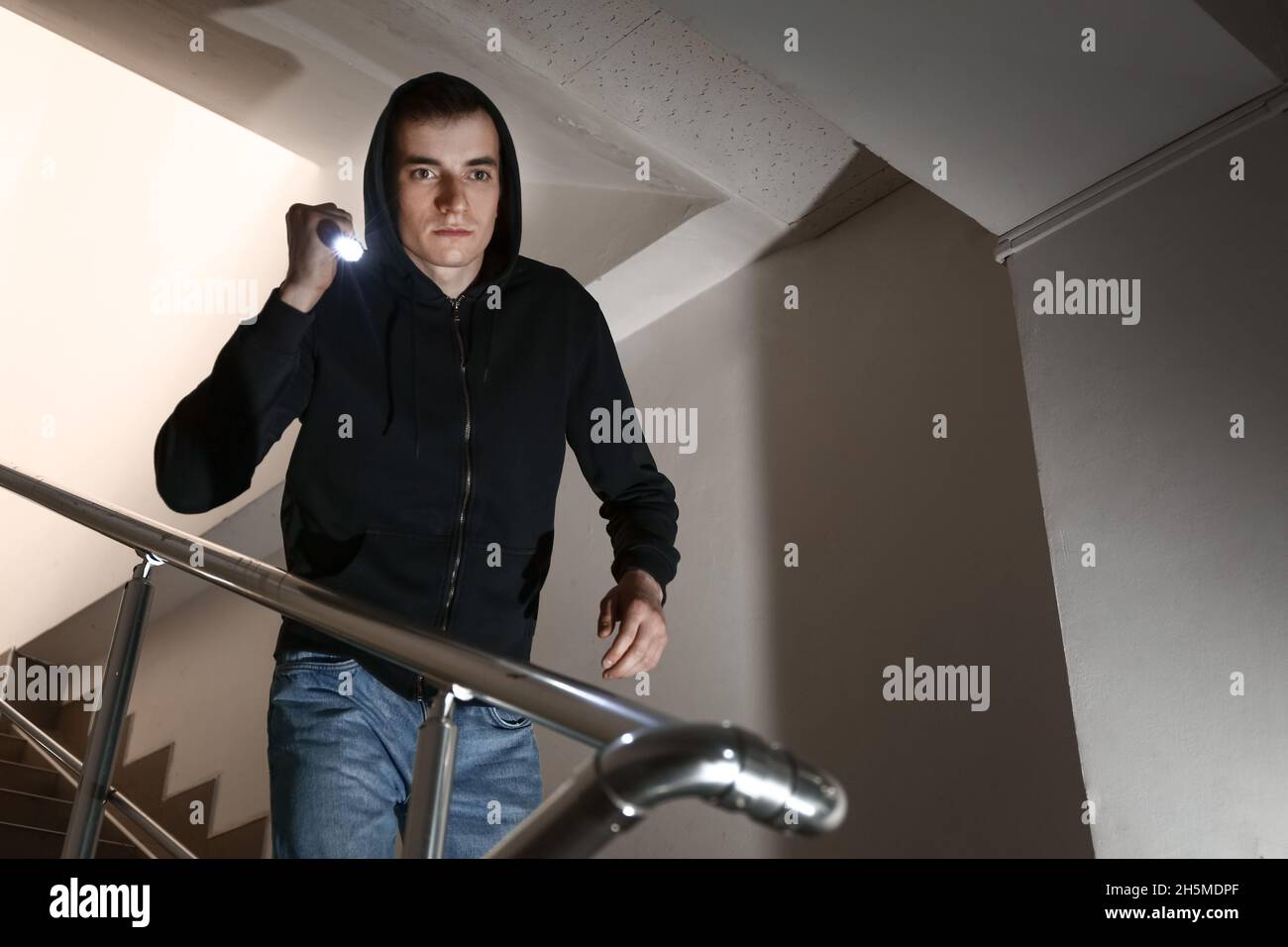 Young man with flashlight in stairway at night Stock Photo - Alamy