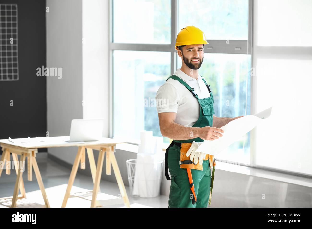 Construction worker with plan of house in room Stock Photo - Alamy