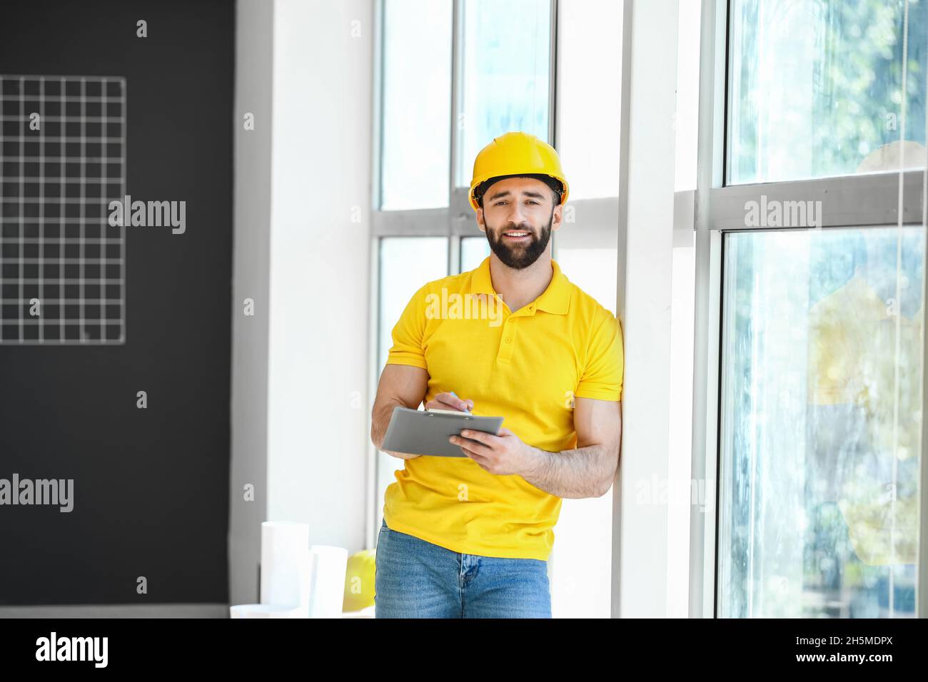 Construction worker writing in clipboard near window Stock Photo - Alamy