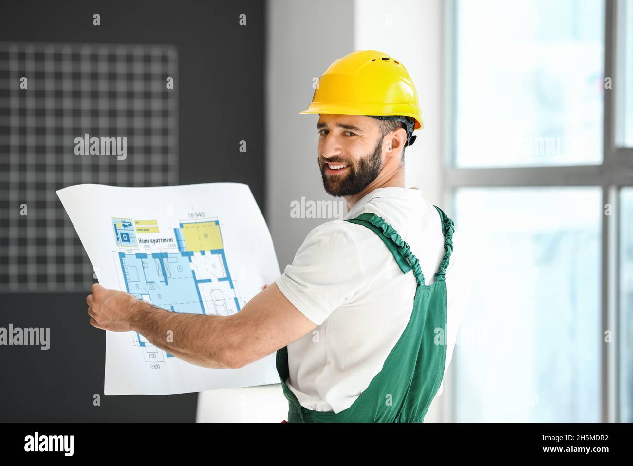 Construction worker with plan of house in room Stock Photo - Alamy