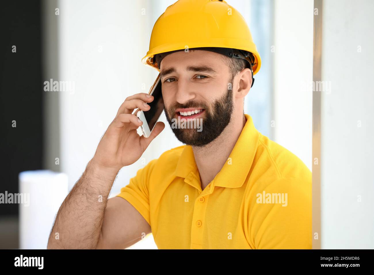 Construction worker talking by mobile phone near window in room Stock ...