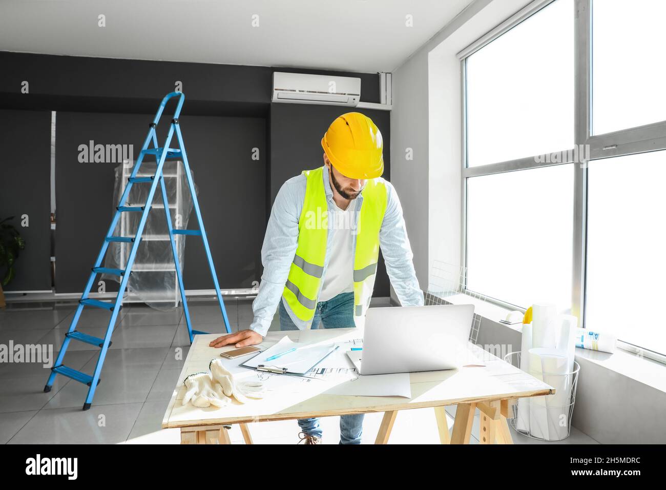 Male builder working near table in room Stock Photo - Alamy