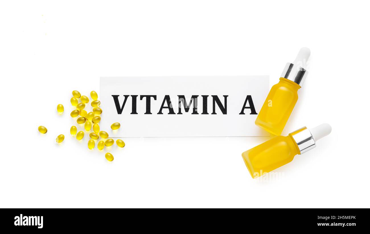 Bottles of essential oil, capsules and paper sheet with text VITAMIN A ...