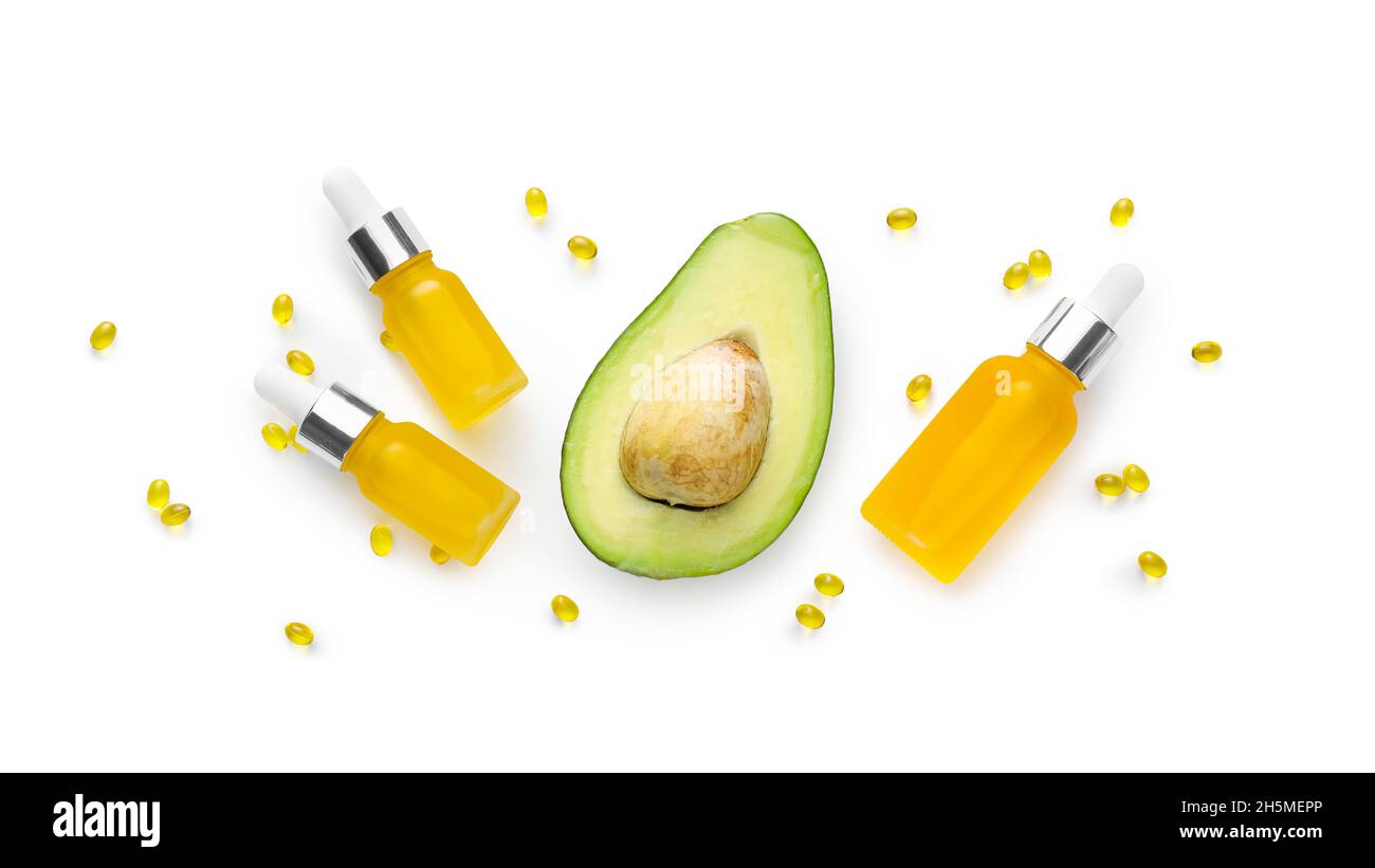 Bottles of essential oil, capsules and avocado on white background ...