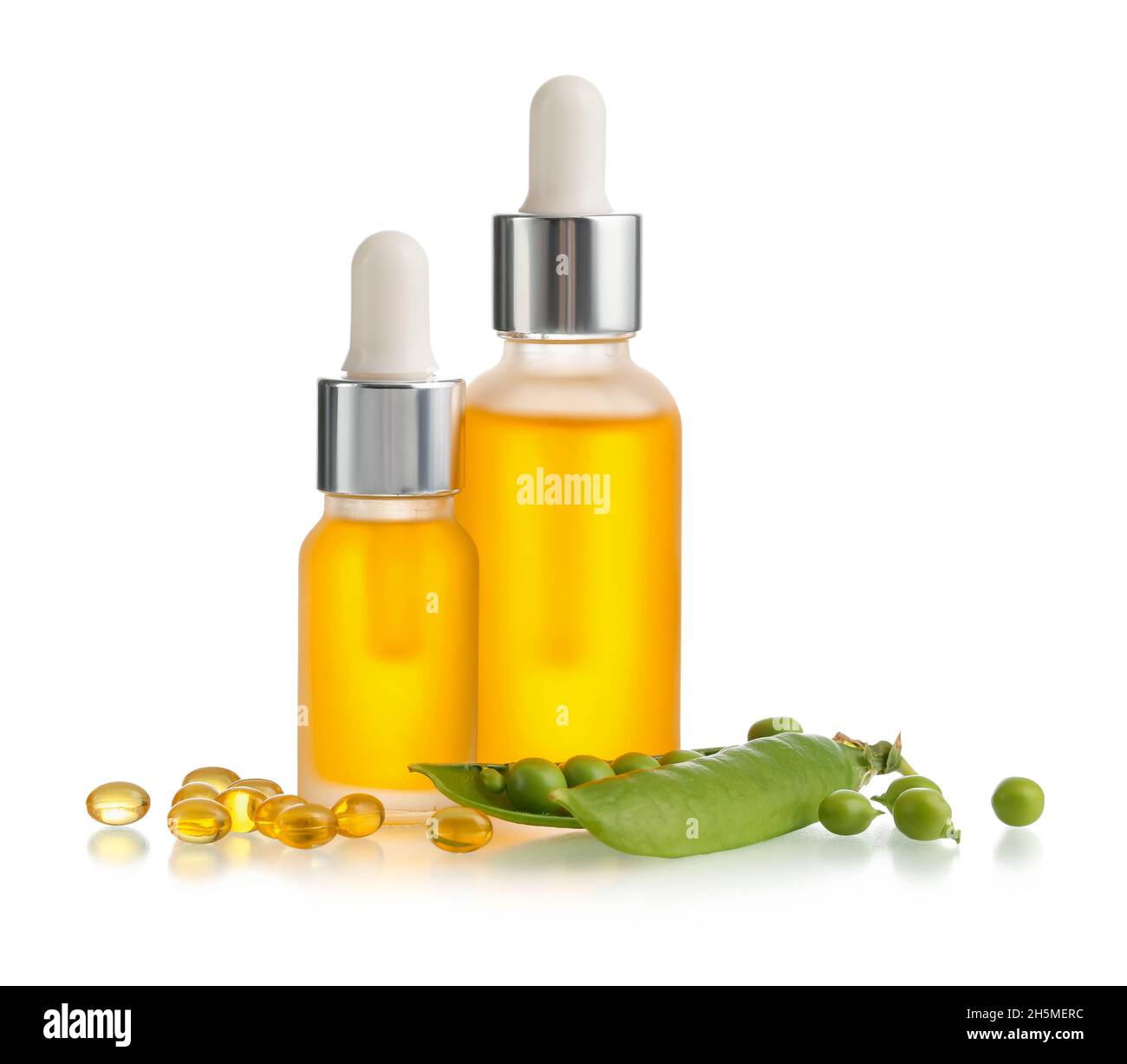 Bottles of essential oil, capsules and green peas on white background ...