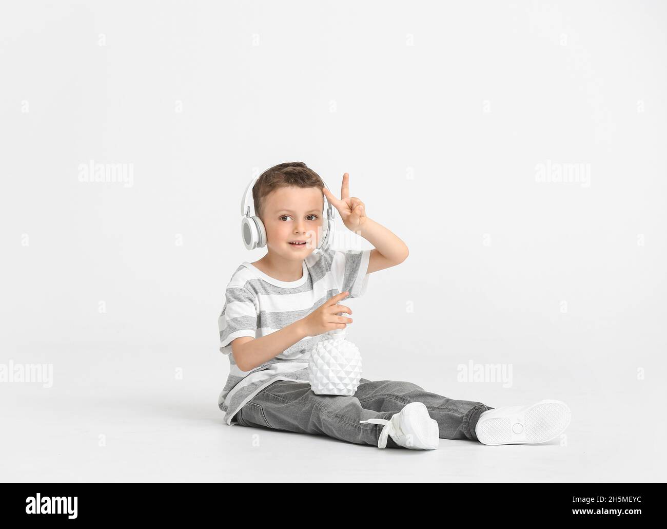Portrait of cute little boy listening to music on light background ...