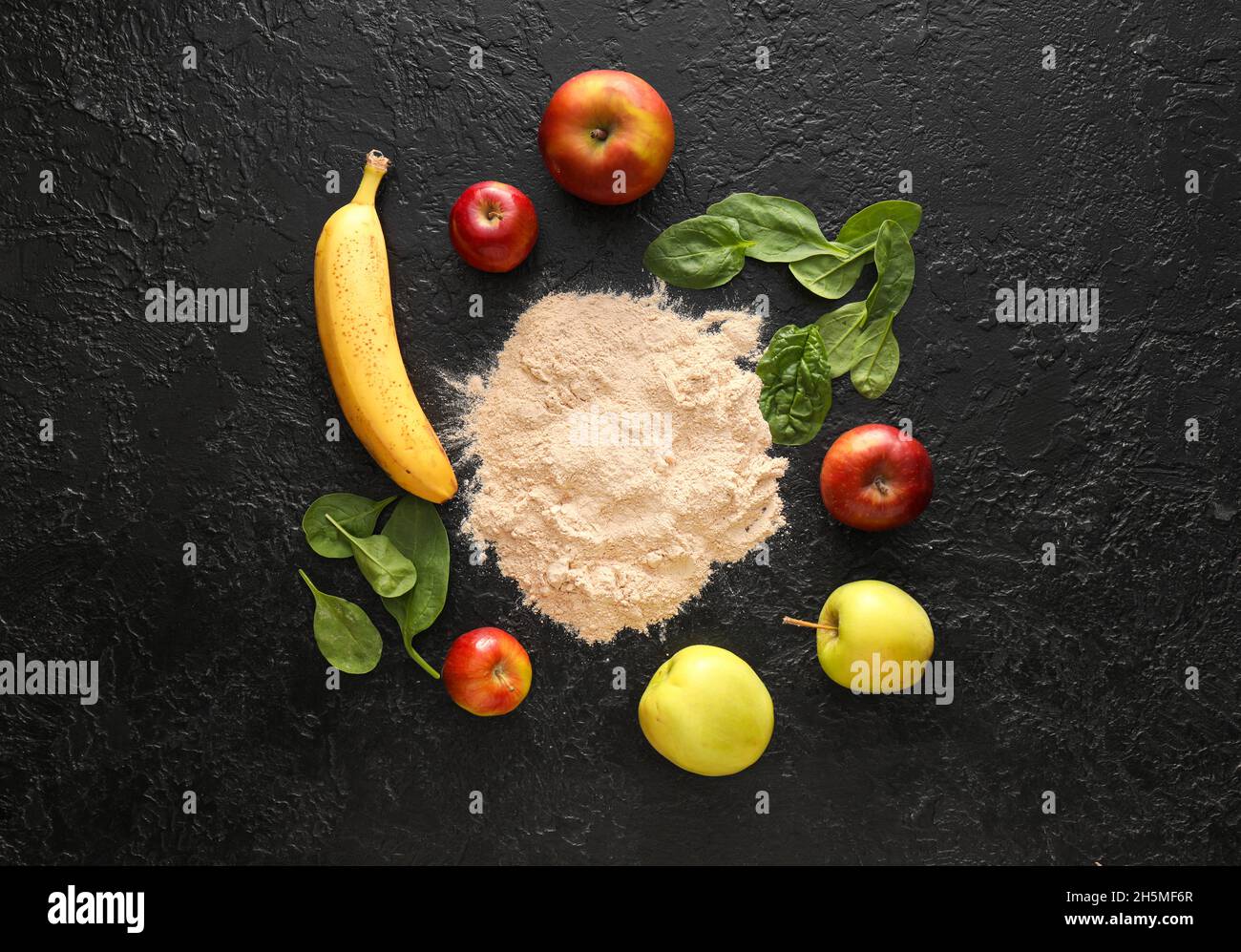 Frame made of apples, banana, spinach leaves and protein powder on dark ...