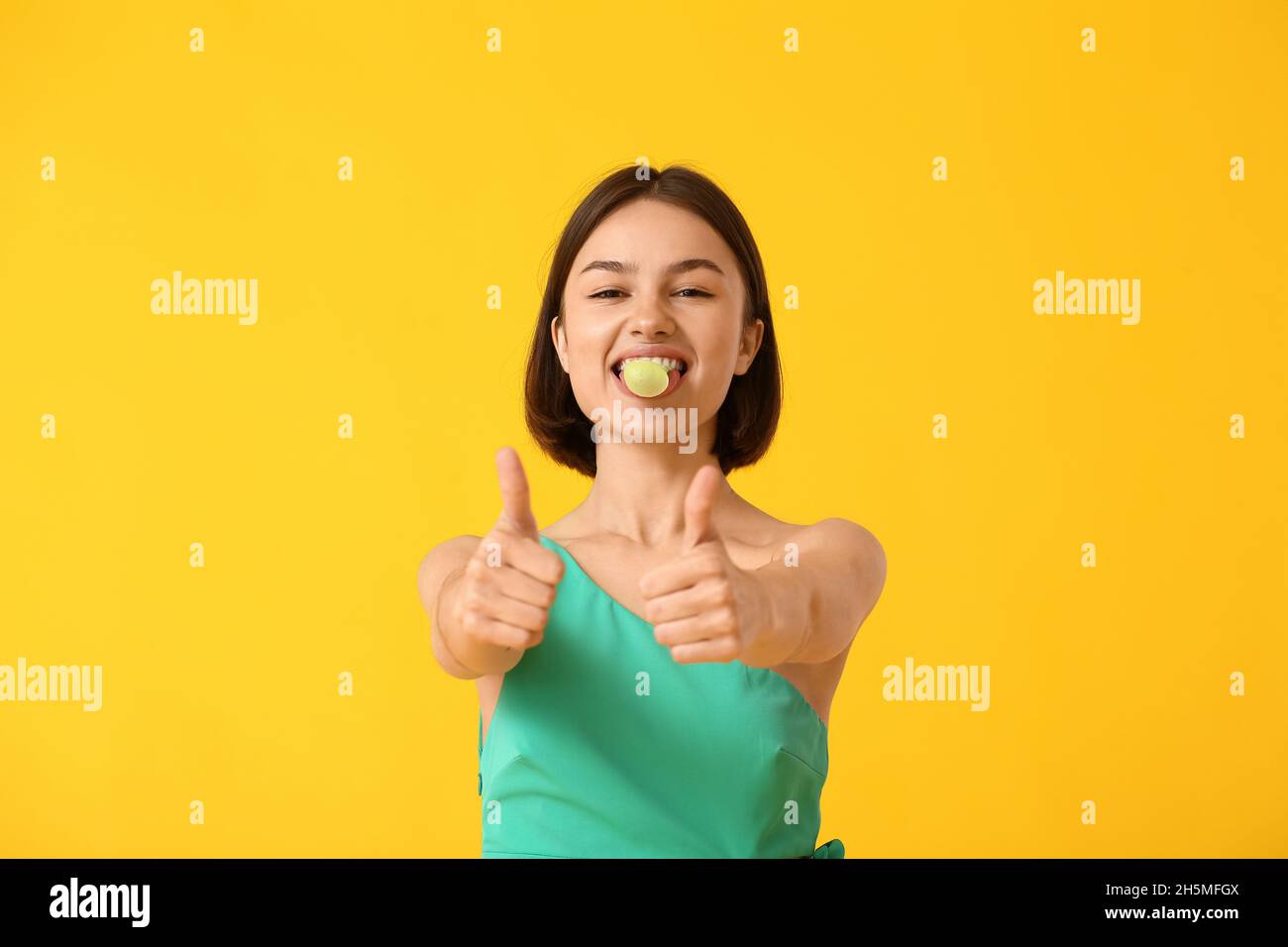 Young woman with chewing gum showing thumb-up on color background Stock ...