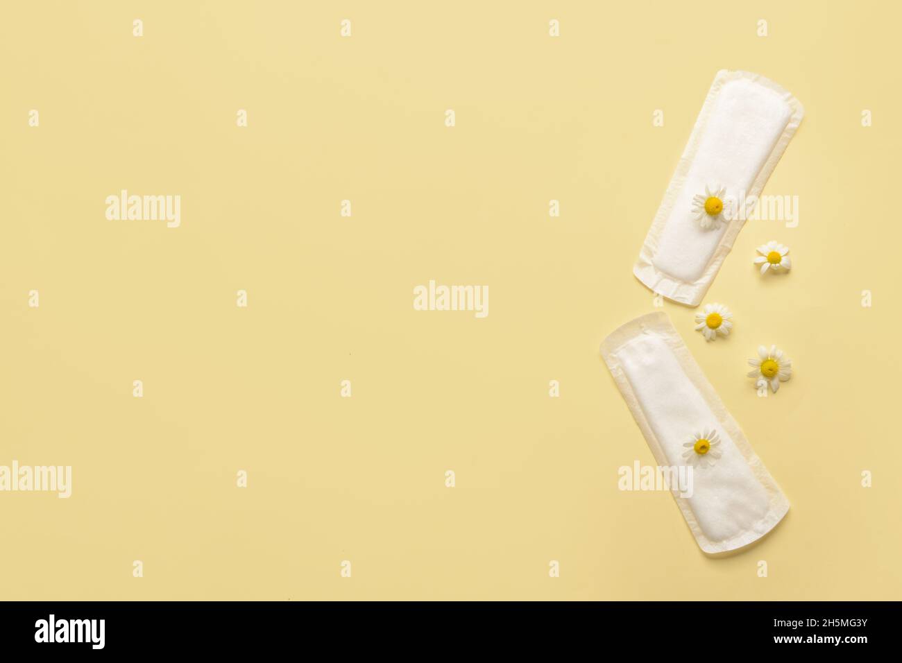 Menstrual pads and chamomile flowers on yellow background Stock Photo ...