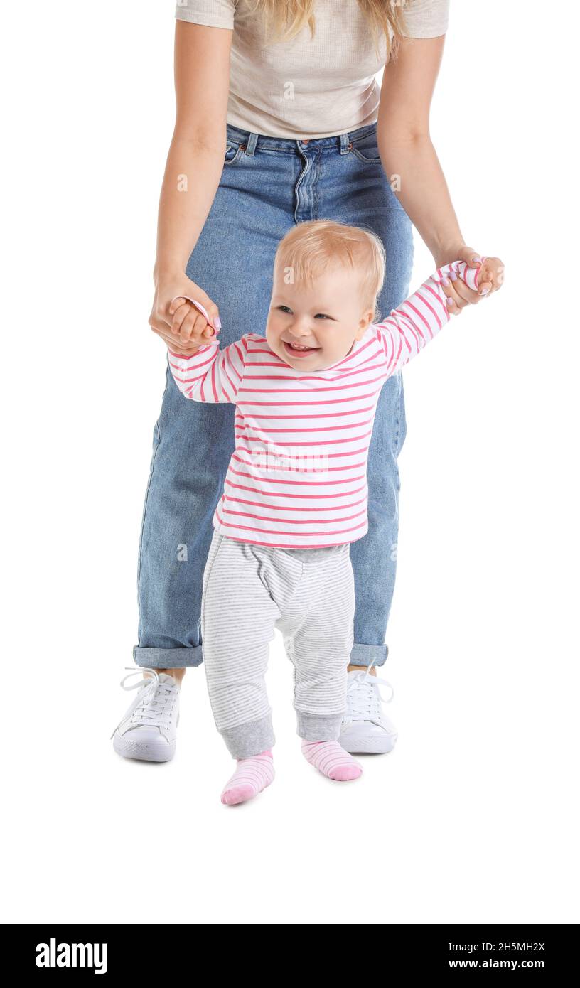 Cute baby girl learning to walk with her mother on white background ...
