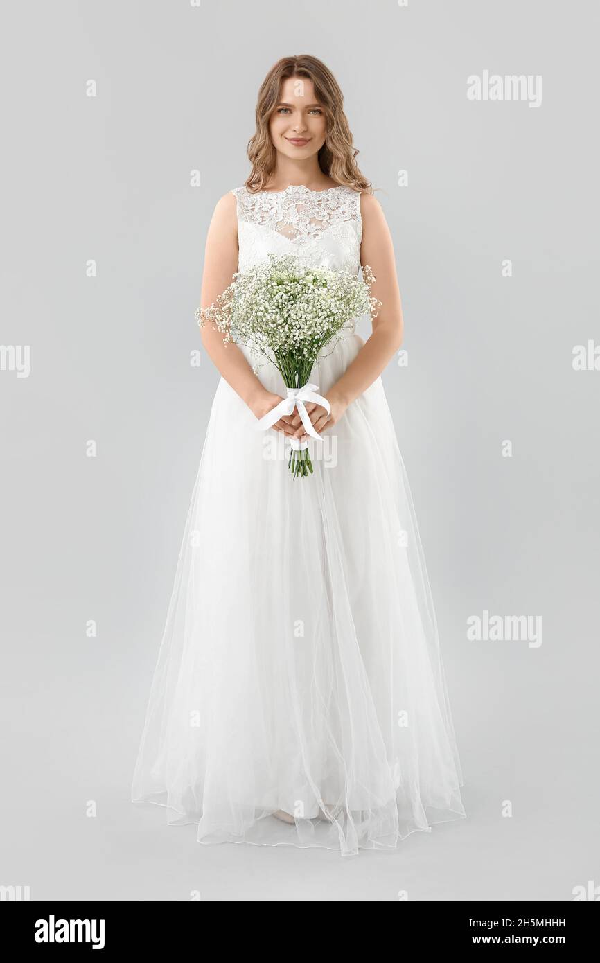 Beautiful bride with bouquet of flowers on light background Stock Photo ...