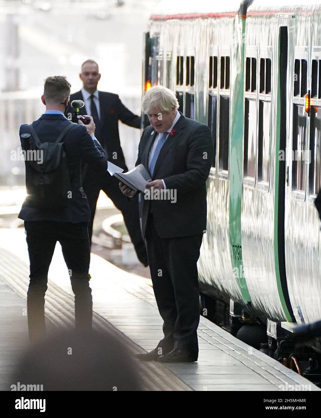 Prime Minister Boris Johnson reads his paperwork as he stands next to a ...