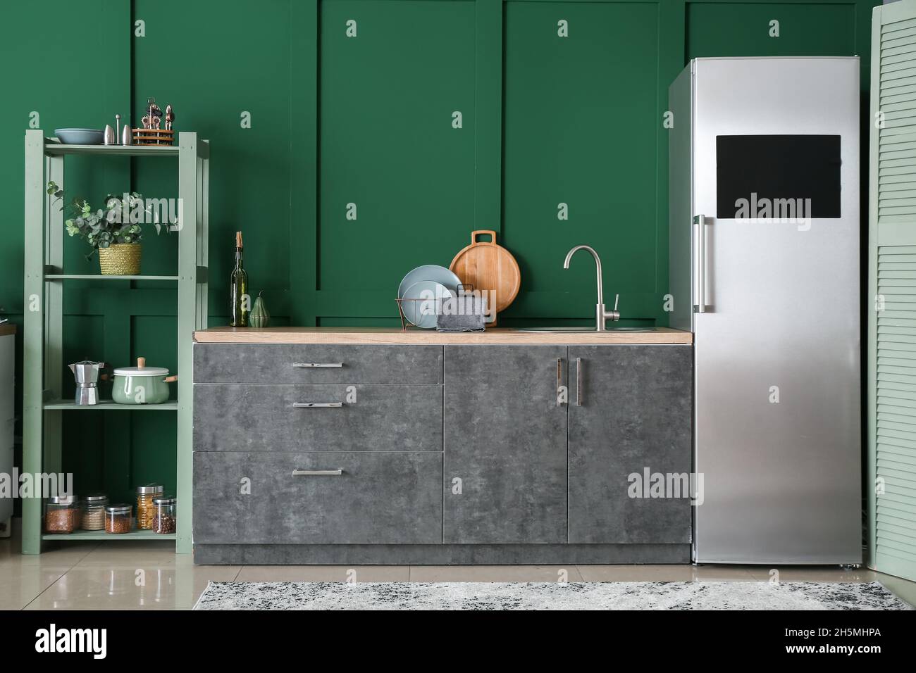 Interior of modern kitchen with fridge and green wall Stock Photo - Alamy