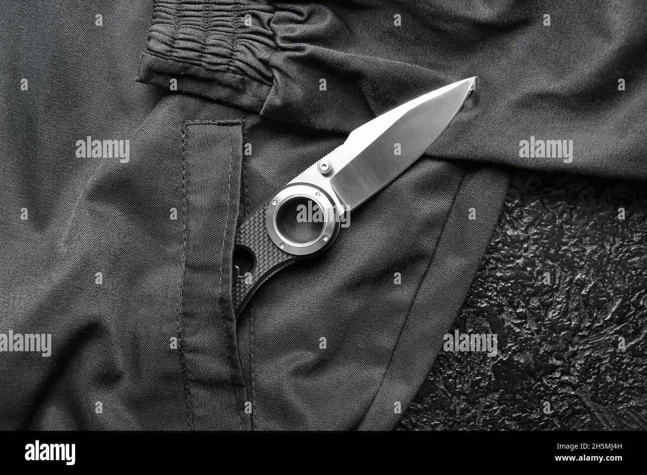 Folding pocket knife with rubberized handle on black suit background ...