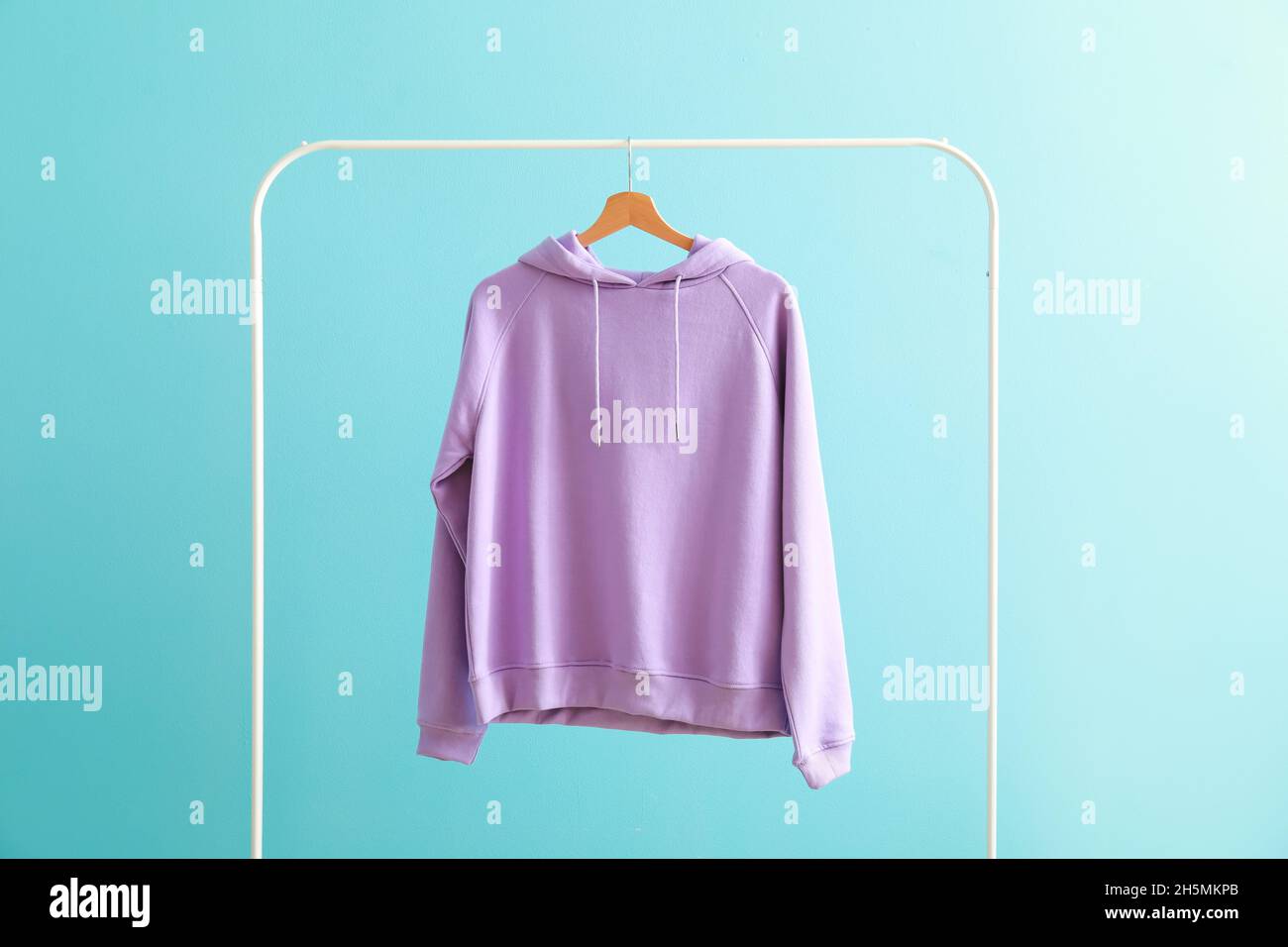 Rack with hoodie on color background Stock Photo - Alamy