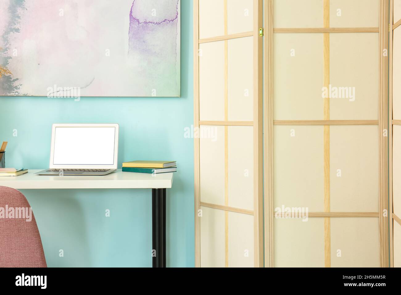 Modern workplace with laptop and folding screen near blue wall Stock ...