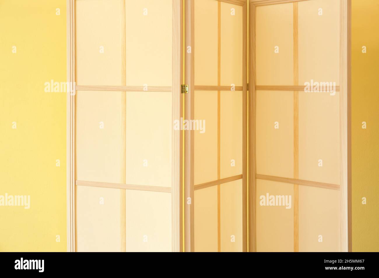 Modern beige folding screen near yellow wall Stock Photo - Alamy