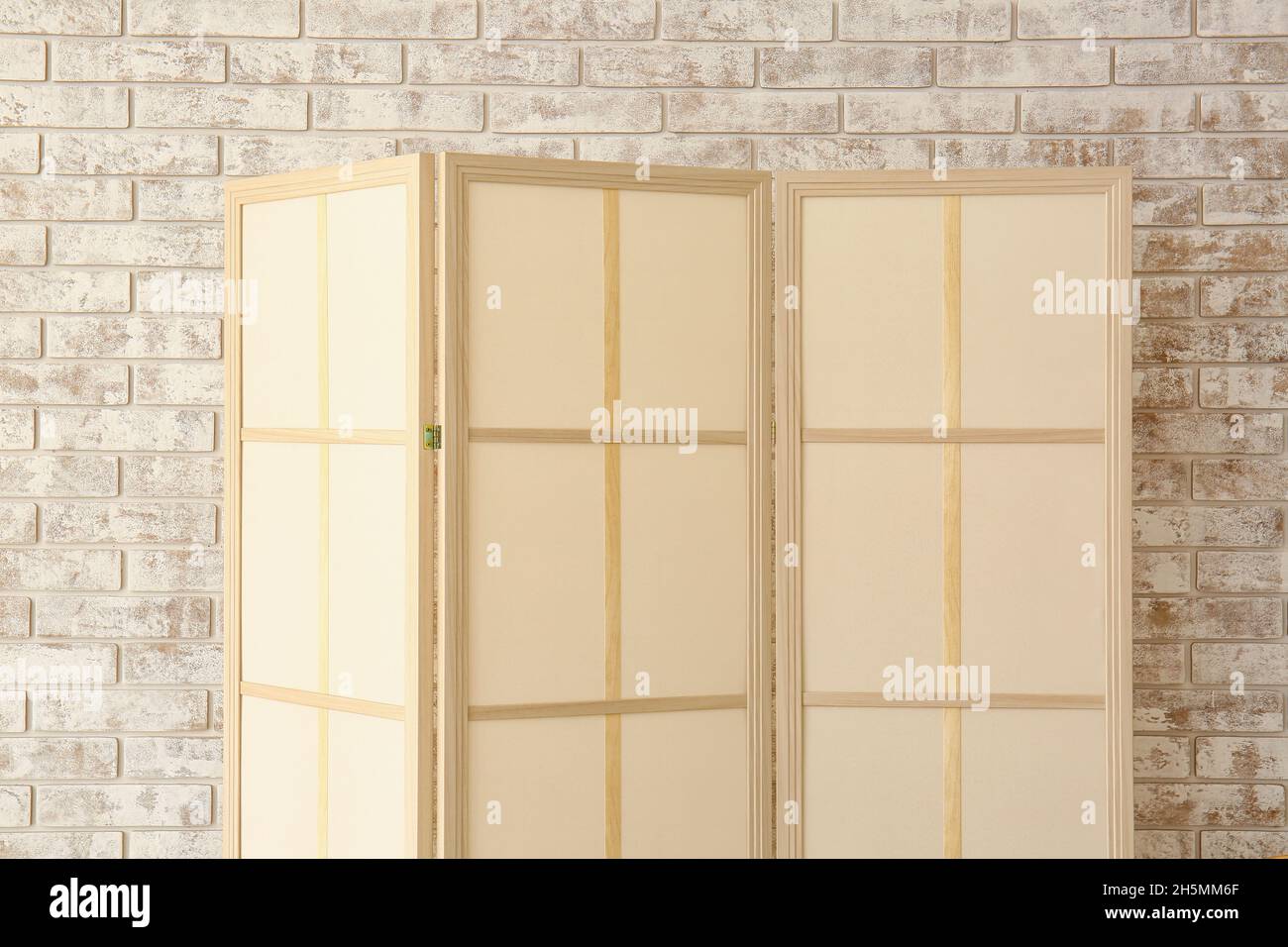 Beige folding screen near light brick wall Stock Photo - Alamy