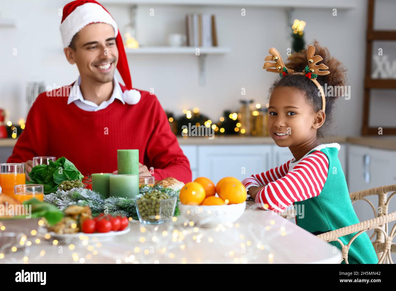 Little girl having Christmas dinner with her father in kitchen Stock ...