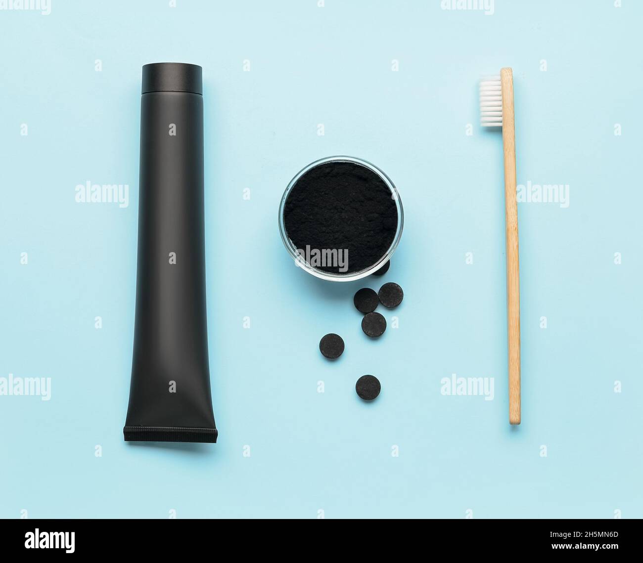 Bowl with activated charcoal tooth powder, toothpaste tube, toothbrush ...