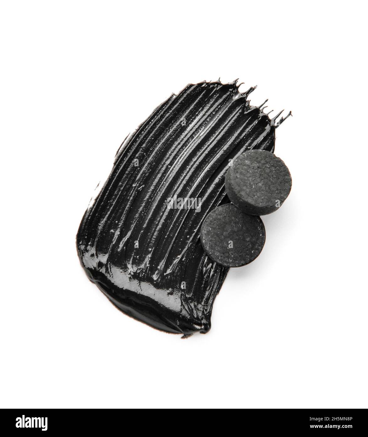 Black activated carbon toothpaste sample and pills on white background ...