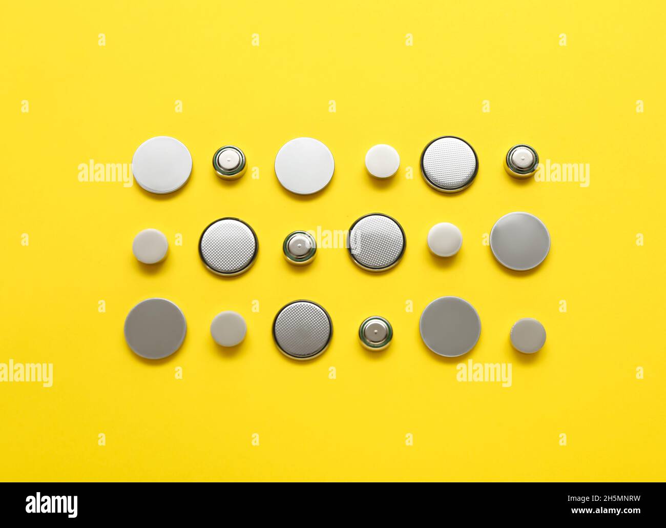 Lithium button cell batteries on yellow background Stock Photo - Alamy