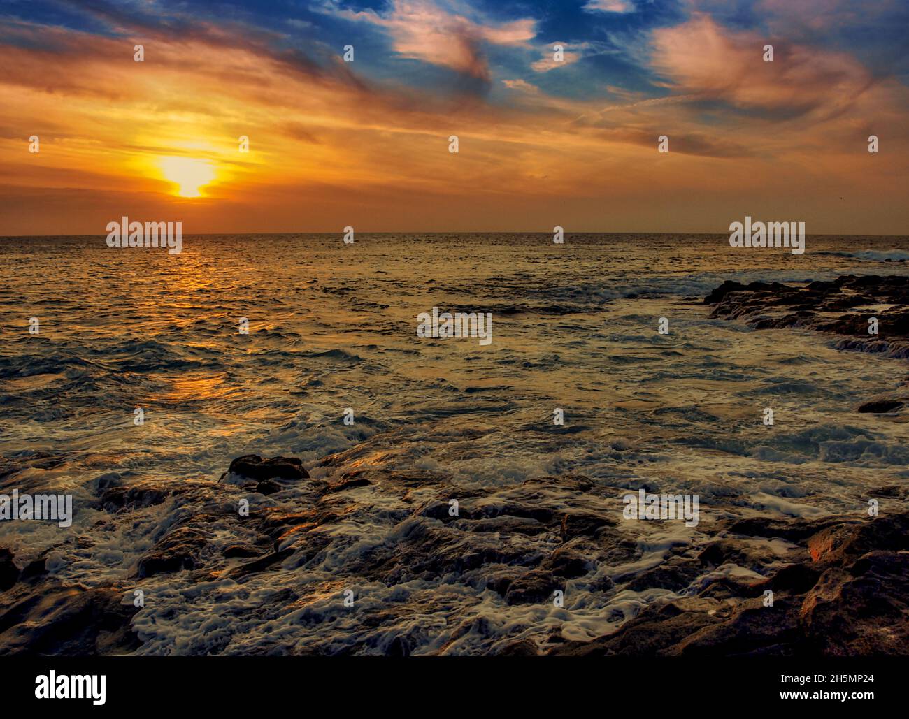 Beautiful shot of a sunset on a sea shore with waves Stock Photo - Alamy